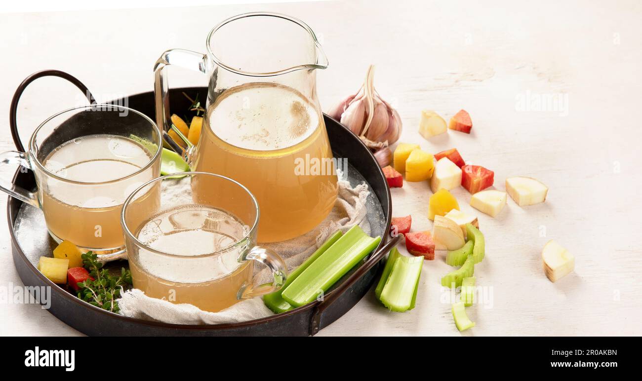 Two cups and glass mug of homemade chicken bone broth on white ...