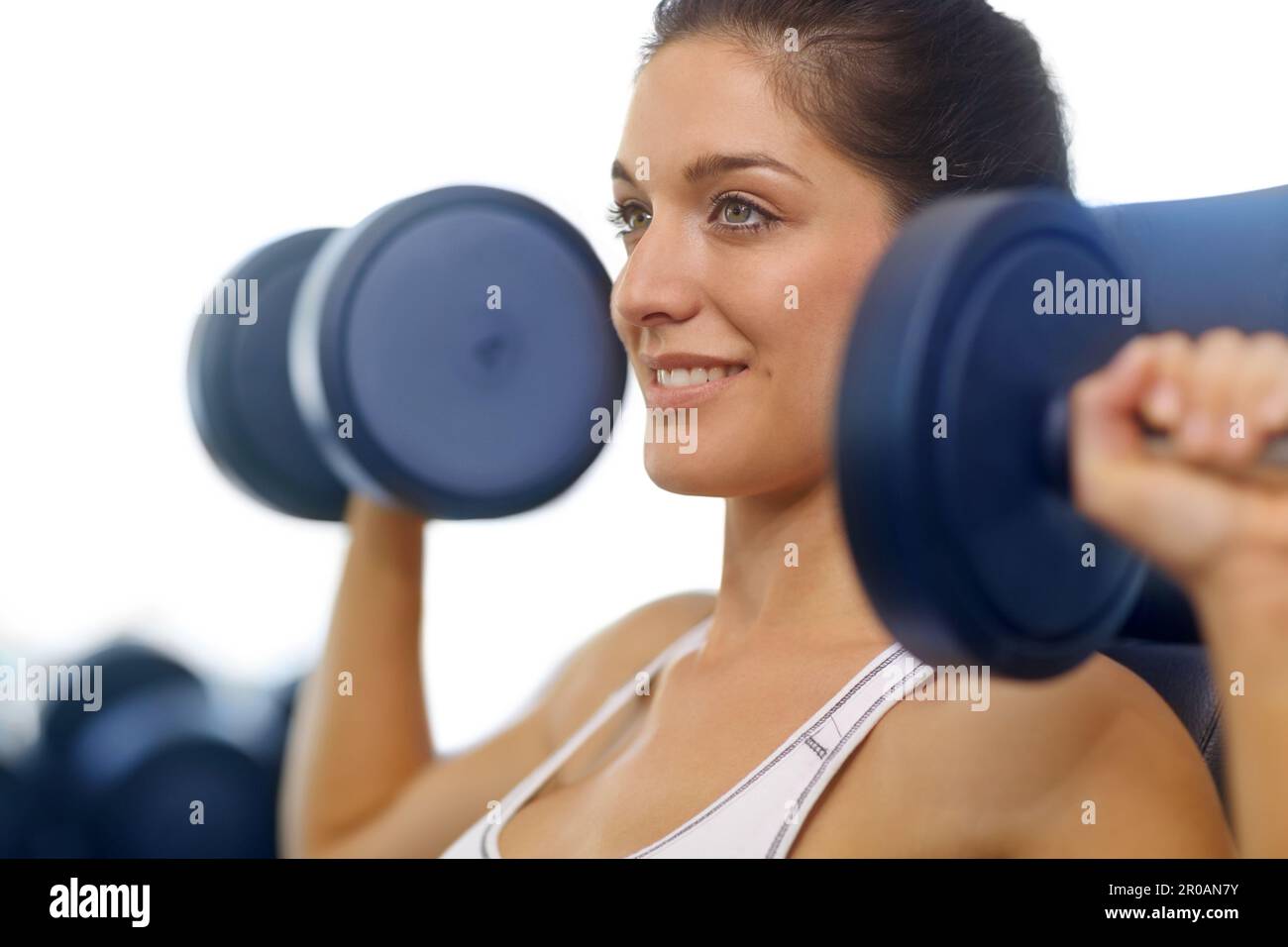 Showing the dumbbells whos boss. A beautiful young woman exercising ...