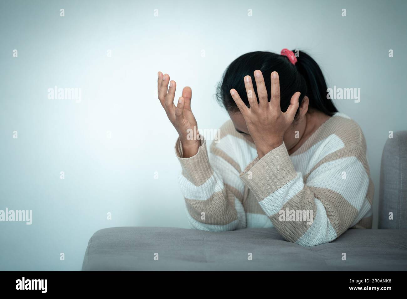 woman kneeling and praying in modern house at sunset time. Female catholic prayer worship to God ...