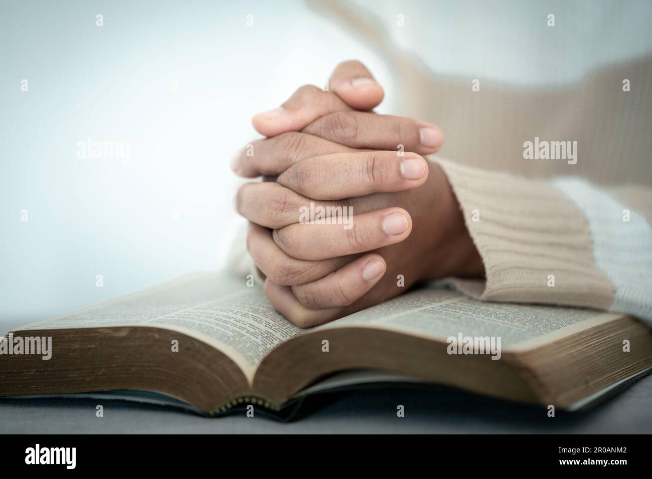 woman kneeling and praying in modern house at sunset time. Female catholic prayer worship to God ...