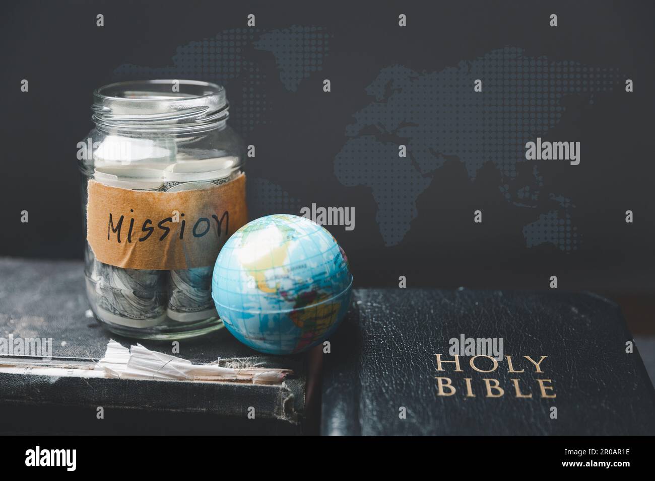 Savings jars full of money and globe with Holy Bible for mission ...