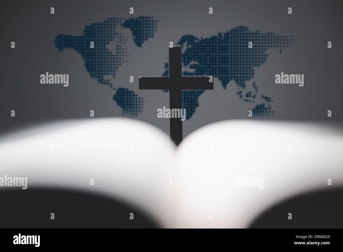 Cross with open Holy Bible on table with world map blur background ...