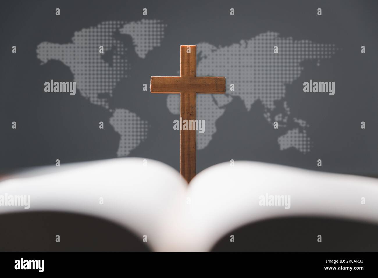 Cross with open Holy Bible on table with world map blur background ...