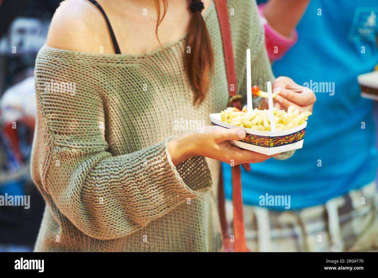 Festival food. a young woman eating french fries at an outdoor festival ...