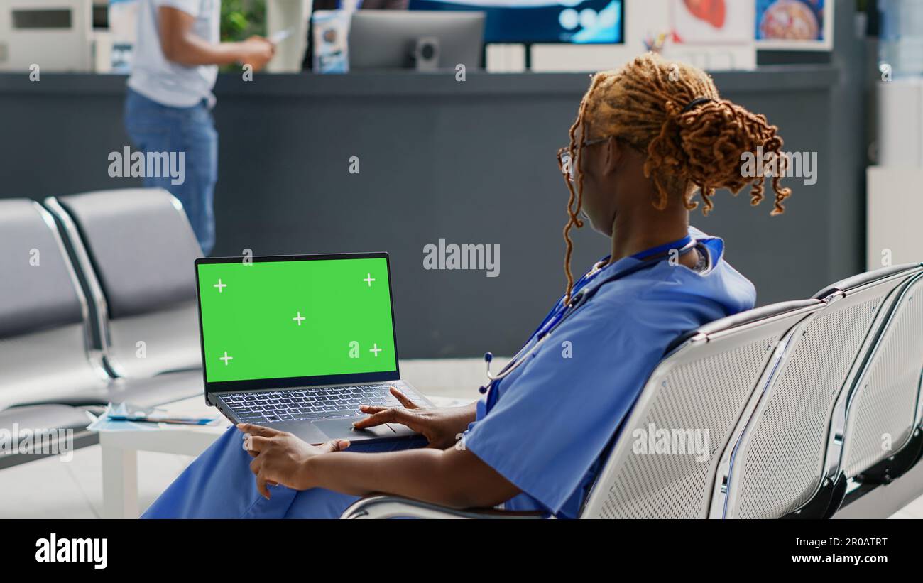 Nurse holding laptop with greenscreen display in waiting room, using ...