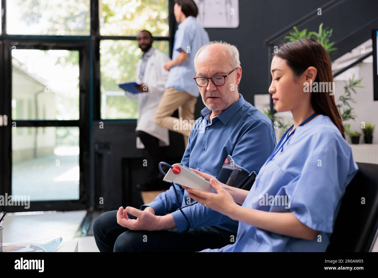 Asian nurse measuring hypertension on tonometer in hospital waiting ...