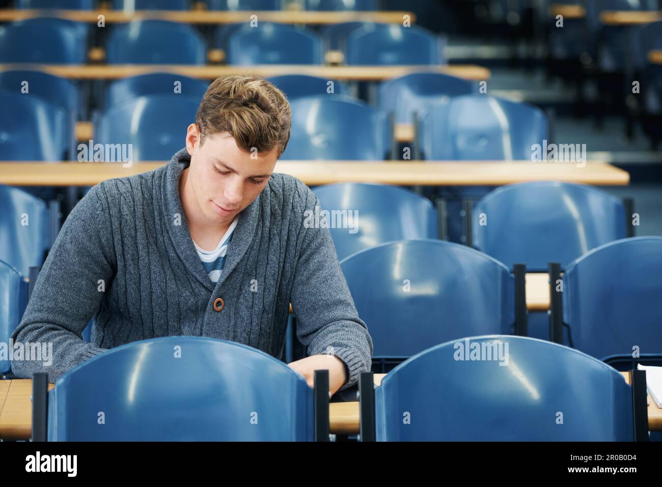 The last student in the lecture hall. A young man sitting alone in a ...
