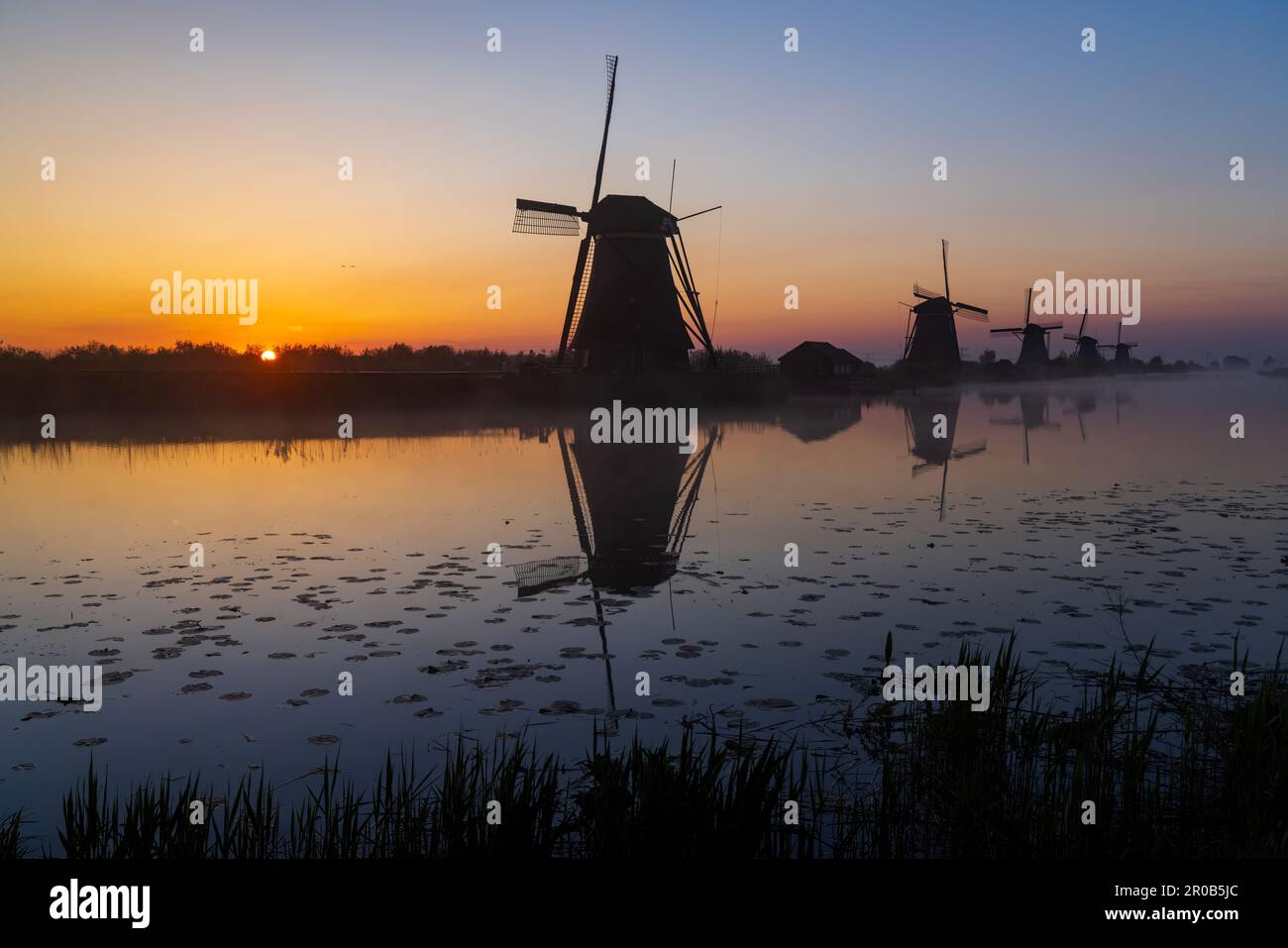 Traditional Dutch windmills with a colourful sky just before sunrise in ...