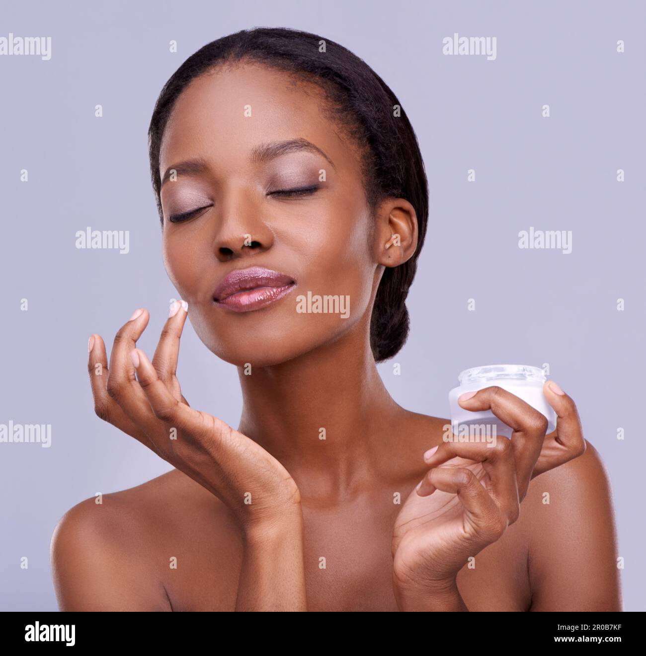 Enhancing her natural beauty. a beautiful young woman against a purple ...