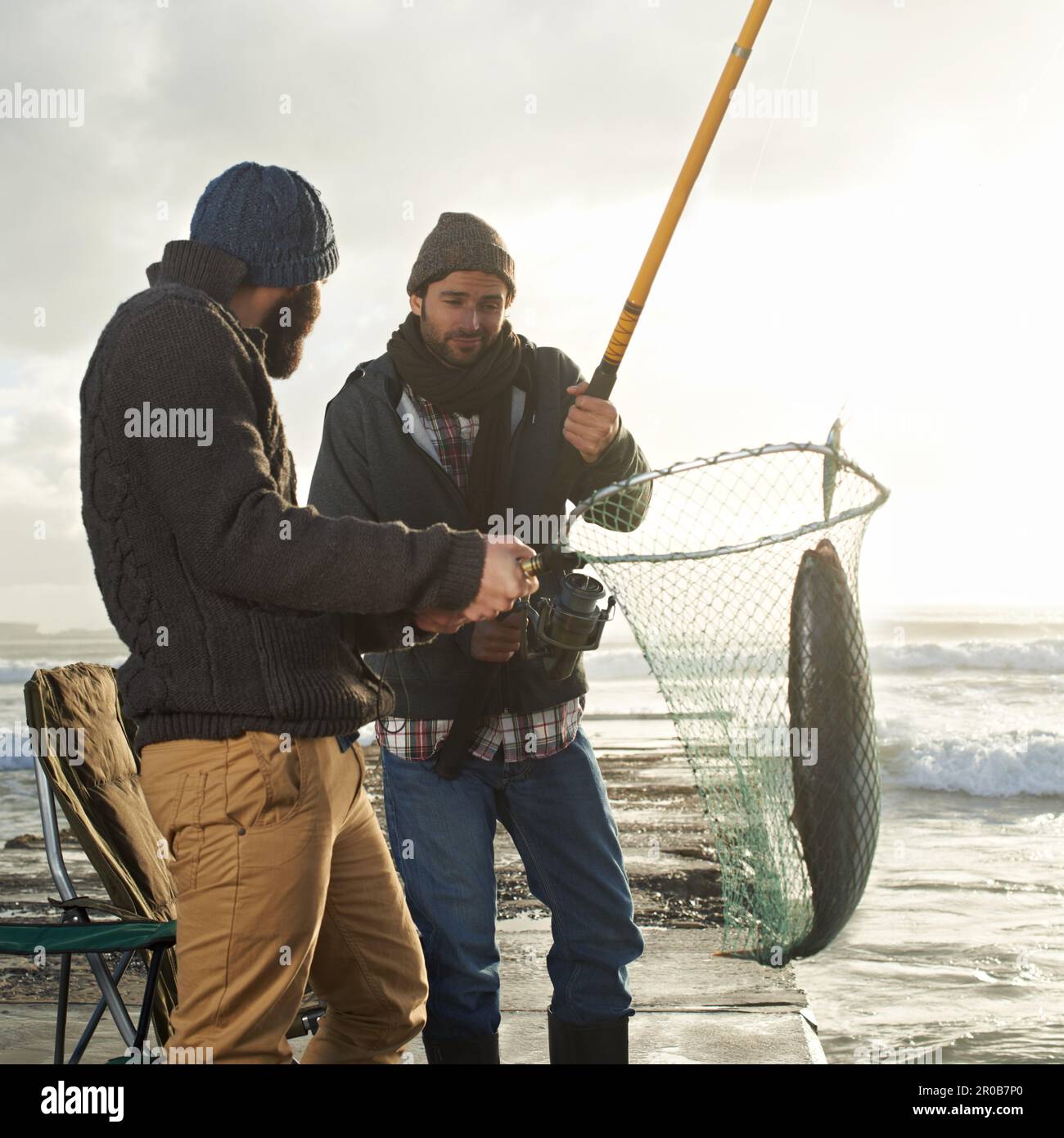 How much to you think it weighs. two young men fishing off a pier with ...