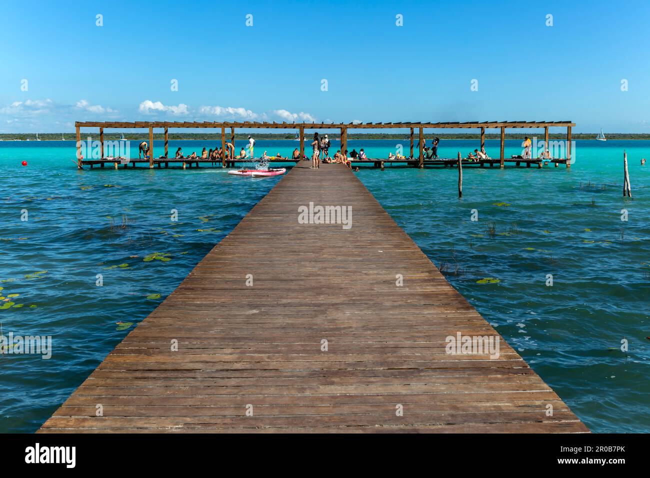 People sitting on woooden jetty pier by waterside, Lake Bacalar ...