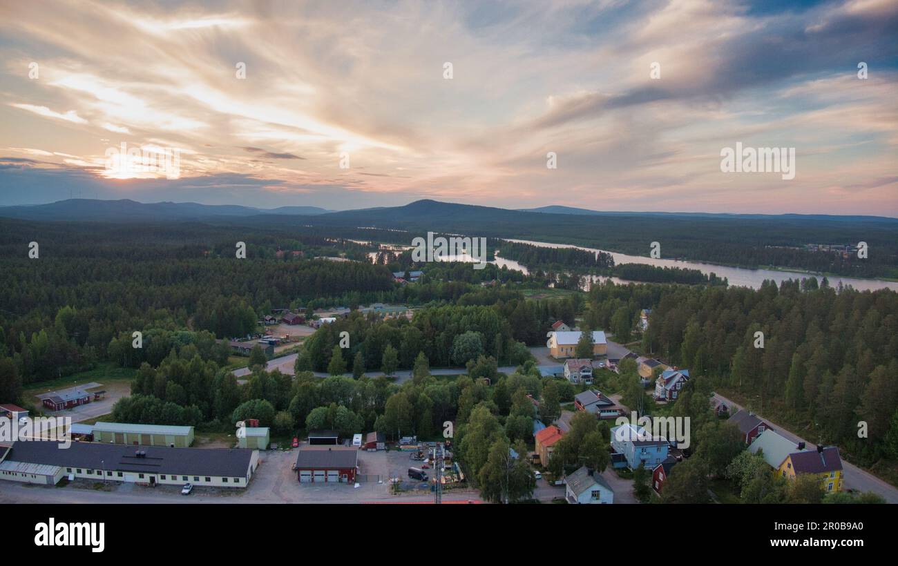 An aerial view of a small town surrounded by a green forest at sunset ...