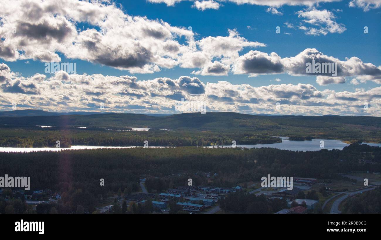 An aerial view of a small town surrounded by a green forest at sunset ...