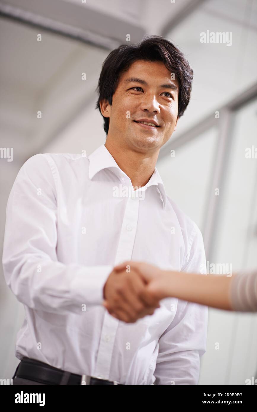 Making a deal. a handsome asian businessman shaking hands with another ...