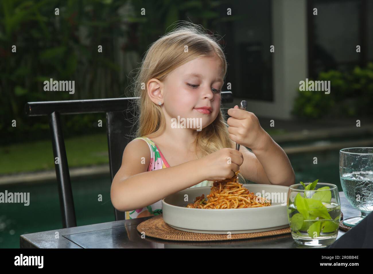 Little girl eating a portion of spaghetti bolognese at the restaurant ...