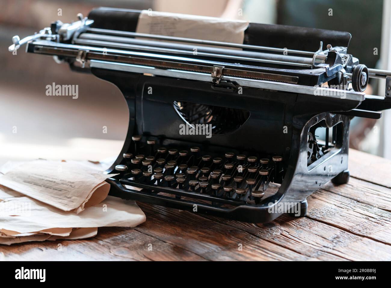 Vintage aged black typewriter with old paper blank on wooden table ...