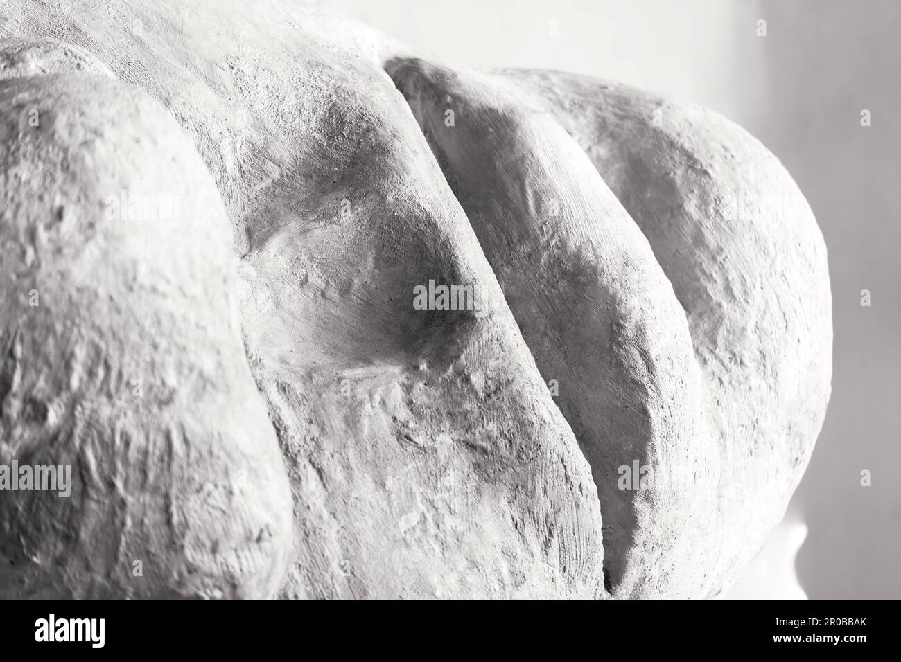 A fragment of plaster human head sculpture against grey background ...