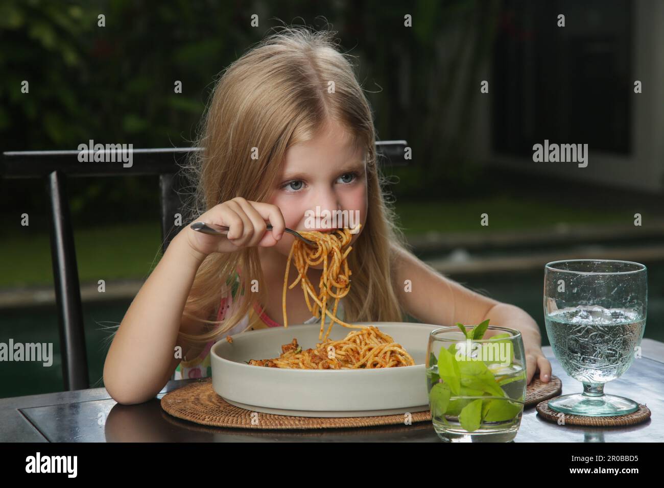 Little girl eating a portion of spaghetti bolognese at the restaurant ...