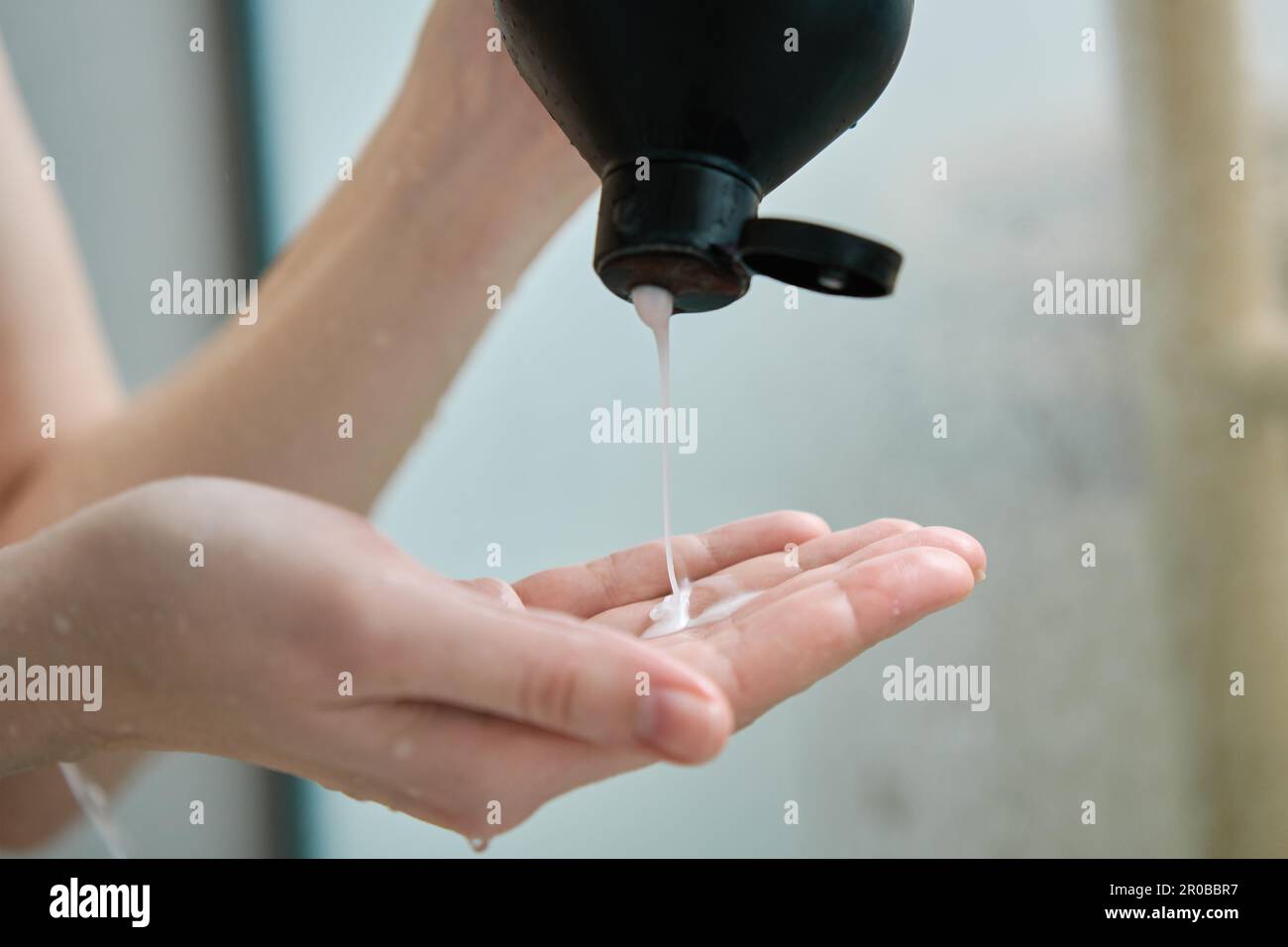 Pouring shampoo from bottle on female hand in bathroom. Hygiene concept ...