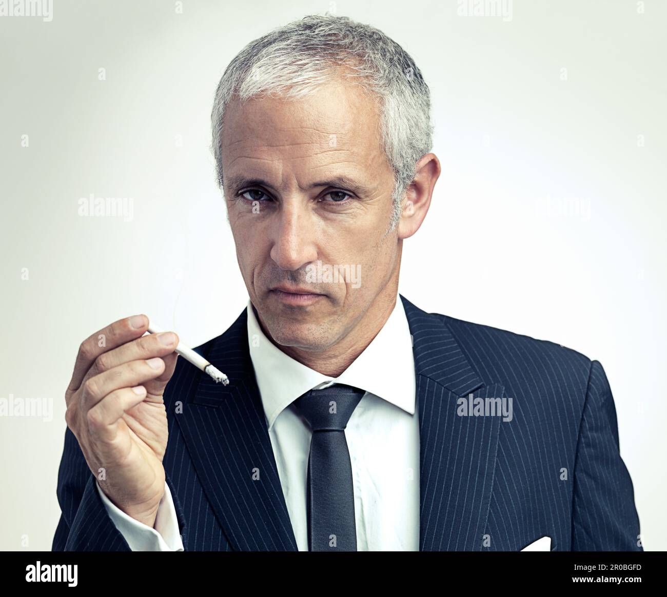 A SUITable moment for a smoke. A cropped portrait of a serious mature ...