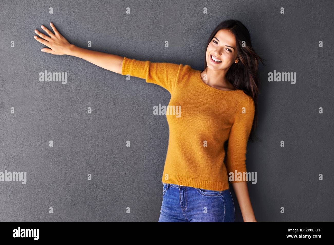 Grabbing your attention. a beautiful young woman against a gray ...