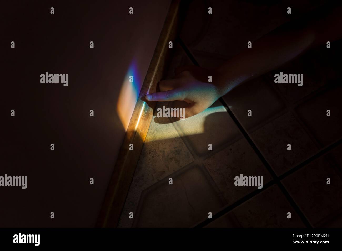 Child touching rainbow light on the wall Stock Photo - Alamy