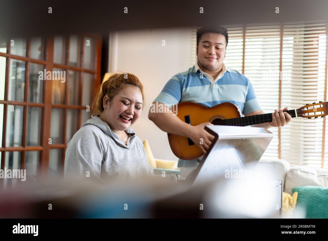Young Asian chubby couple singing and playing acoustic guitar and piano ...