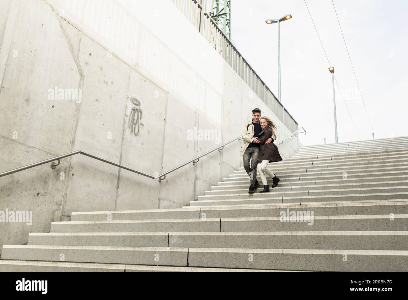 Young couple walking down the stairs hugging each other, Munich ...