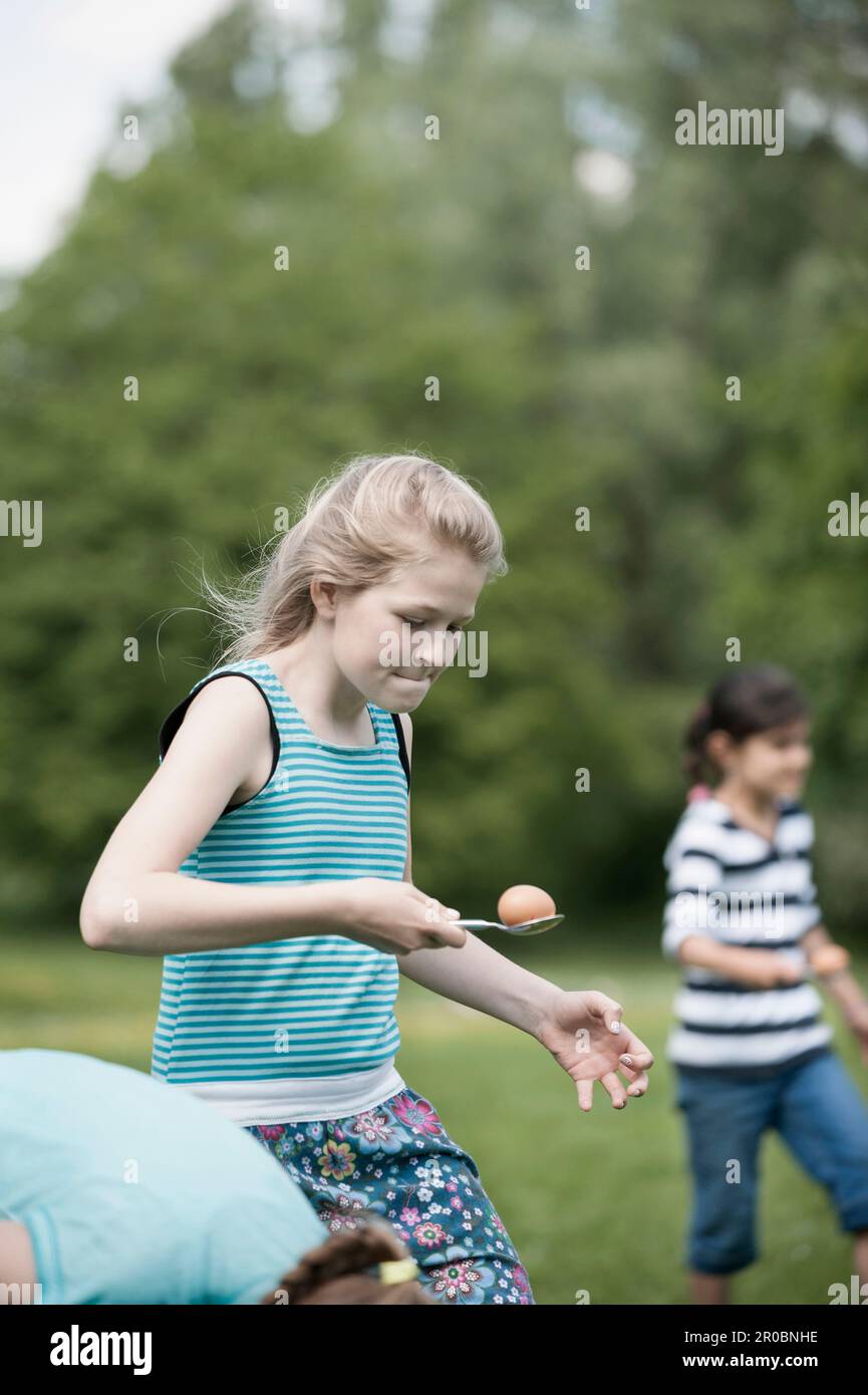 Group of girls competing in an egg-and-spoon race in a park, Munich ...
