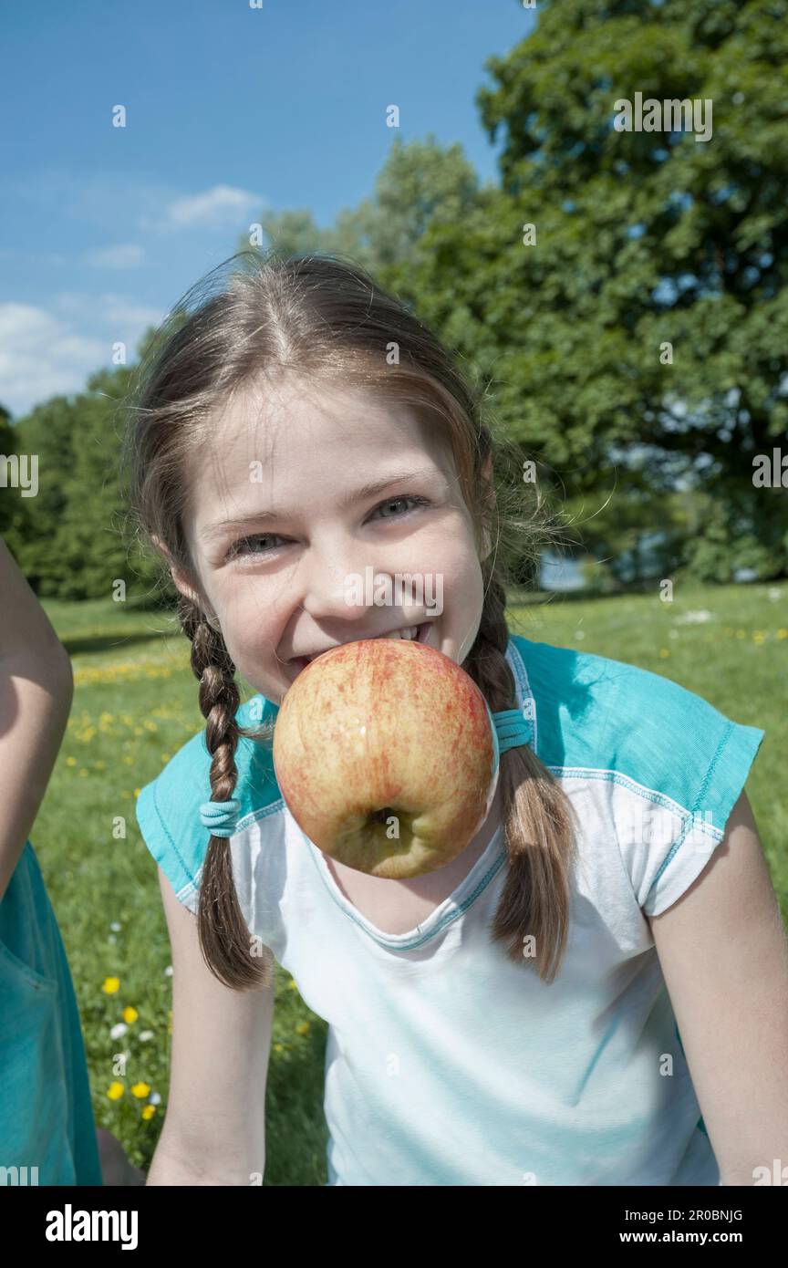 Portrait of a girl with apple in her mouth and smiling, Munich, Bavaria ...