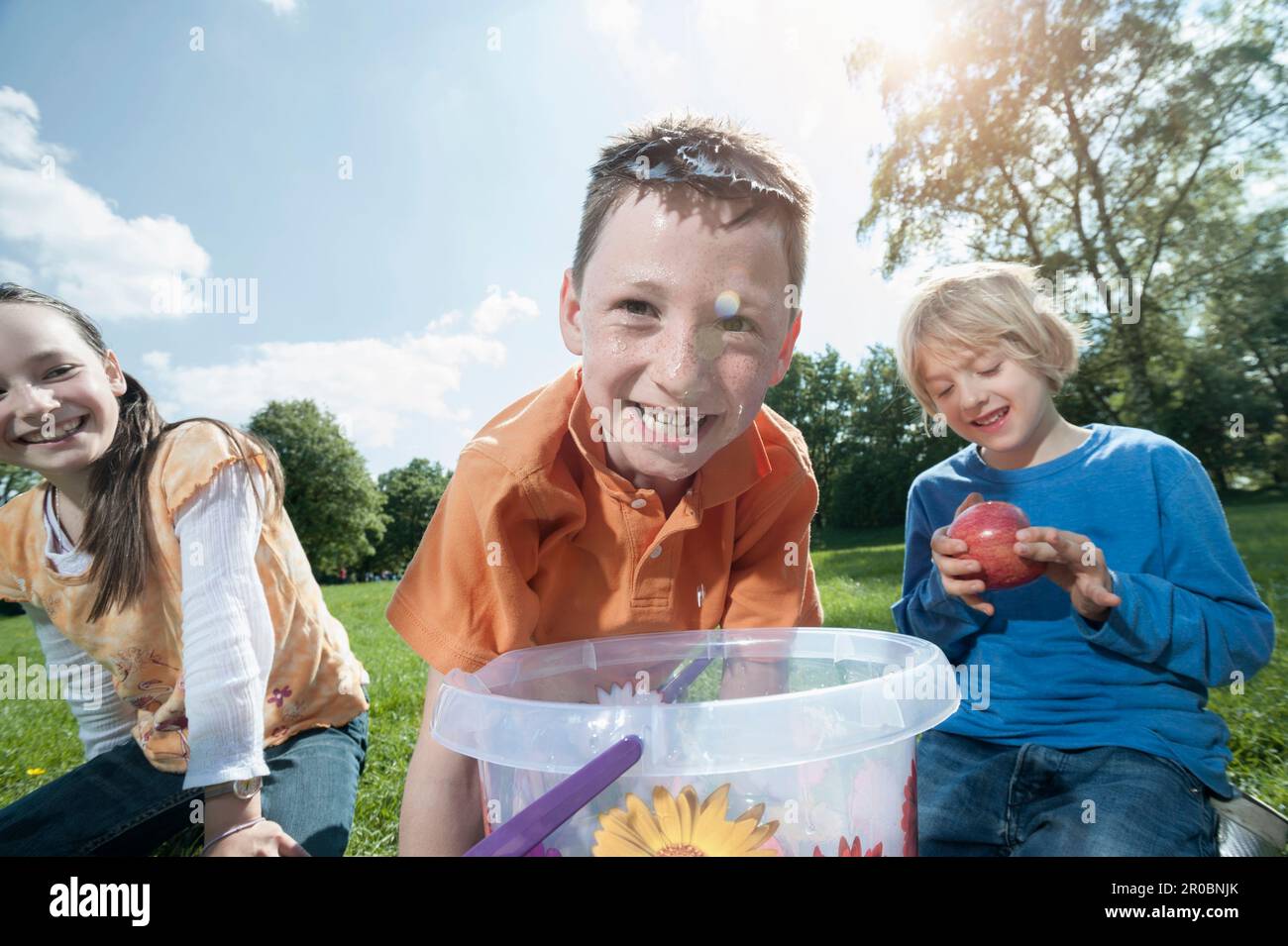 Boy trying to take apple out of a bucket with their mouth, Munich ...
