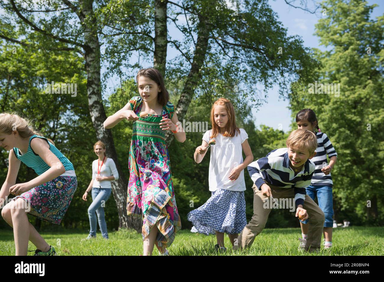 Group of children competing in an egg-and-spoon race in park, Munich ...