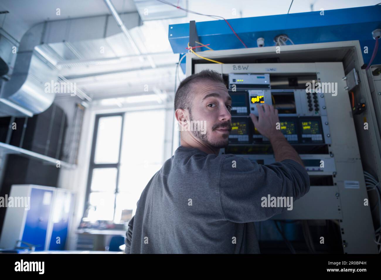 Portrait of a young male engineer controlling a switchgear in control ...