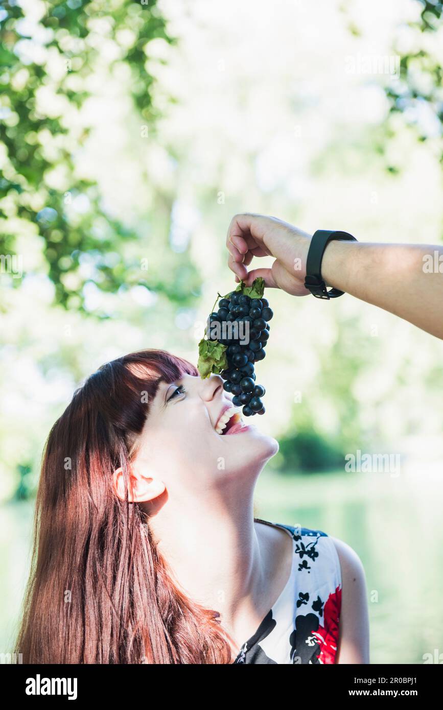 Man feeding grape to woman at lakeshore in the English Garden, Munich, Germany Stock Photo - Alamy