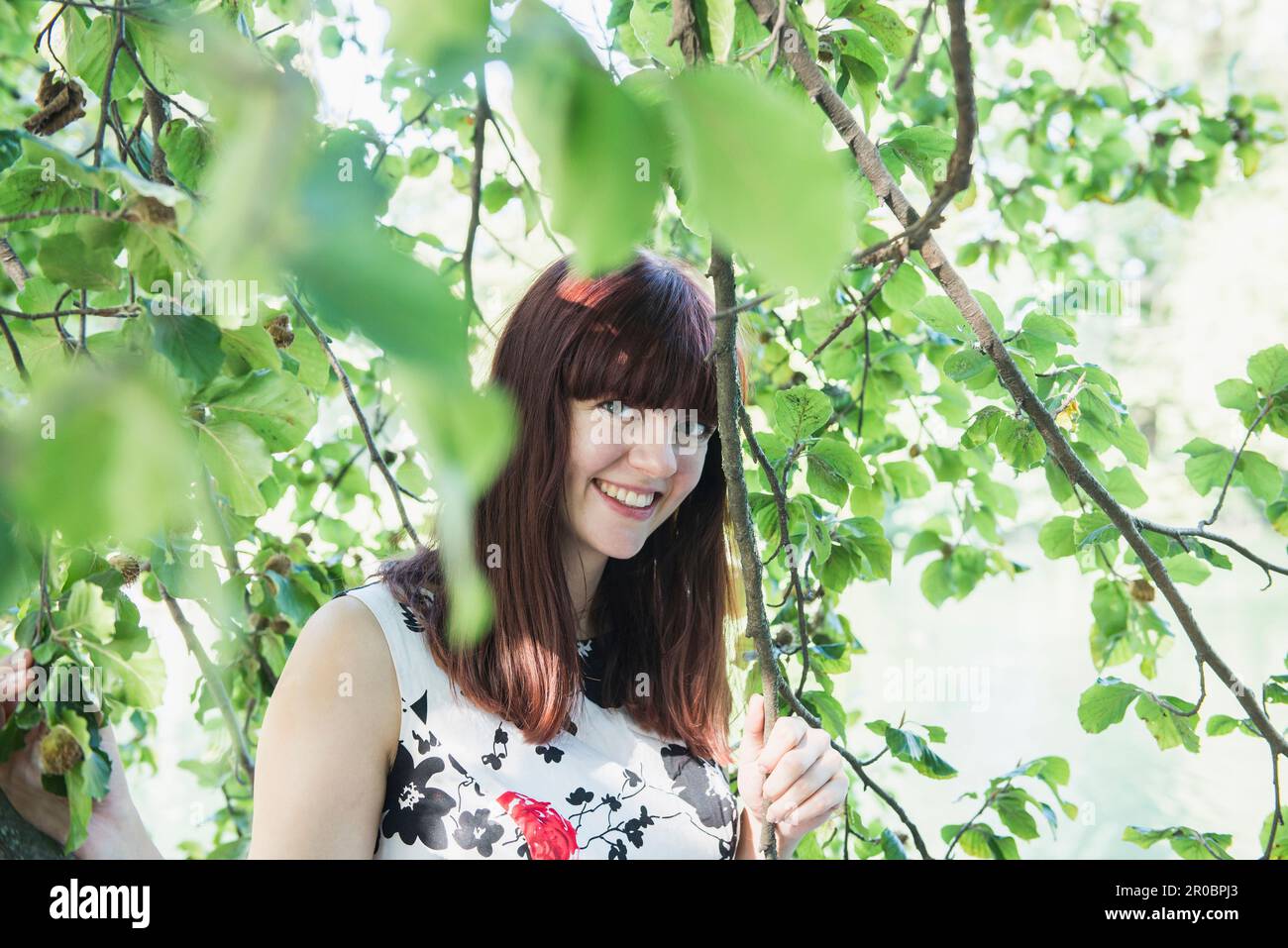 Portrait of a smiling young woman under a tree Stock Photo - Alamy