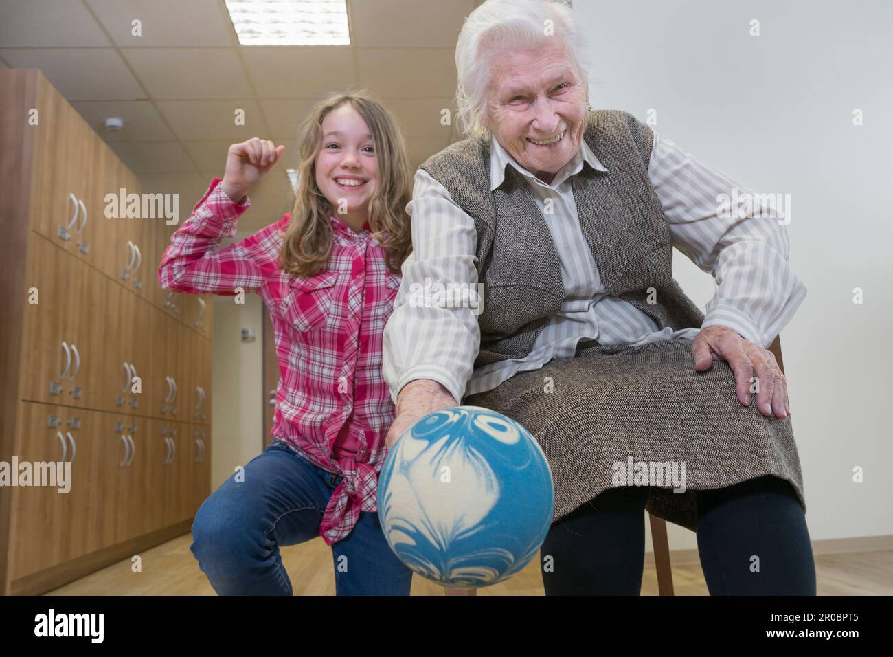 Girl playing bowling with senior woman in rest home Stock Photo - Alamy