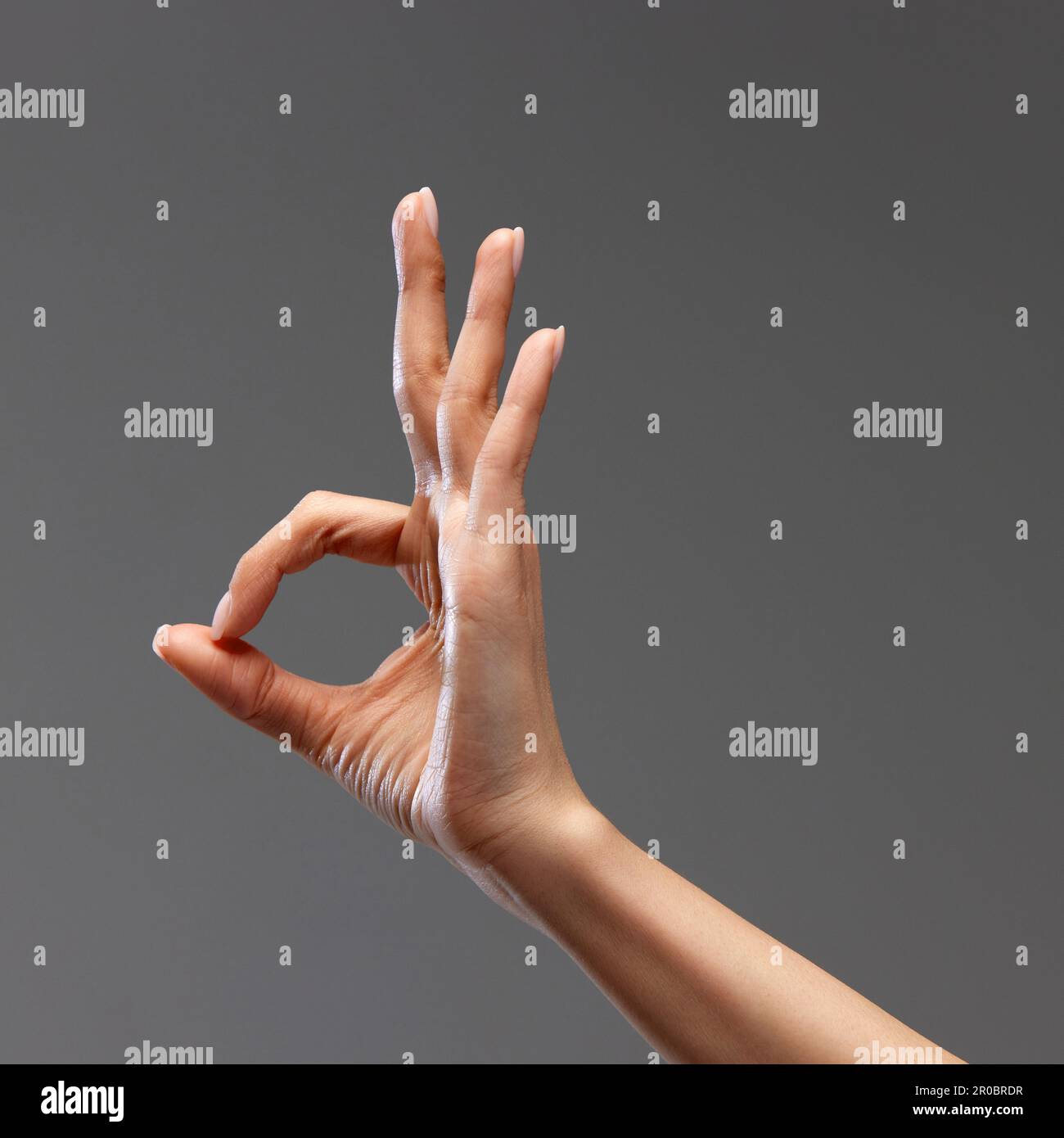 Female hand showing gesture of OK against grey background. Good time ...