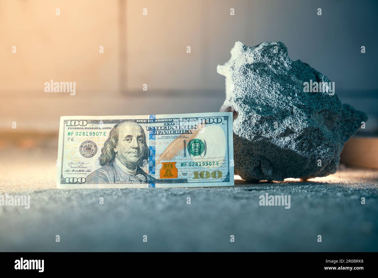 One hundred dollars and a chipped piece of aerated concrete brick close ...