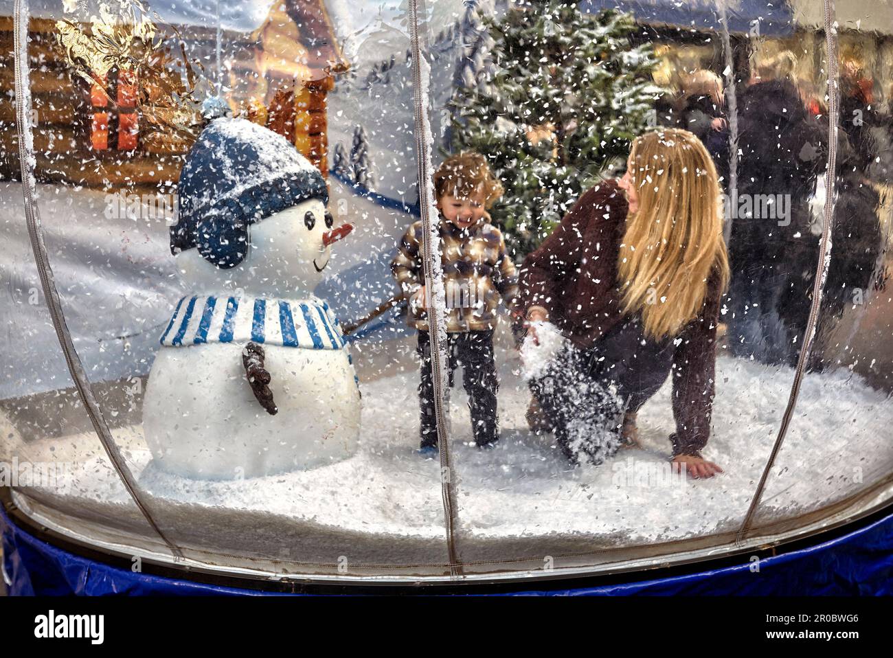 Mother child playing together with artificial snow in a plastic bubble ...