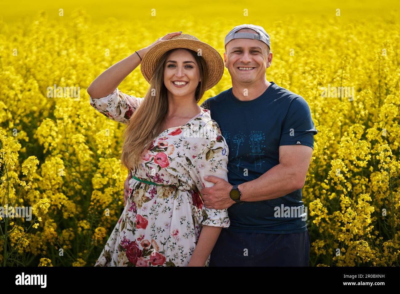 Happy farmers couple standing together by a blossoming canola field ...