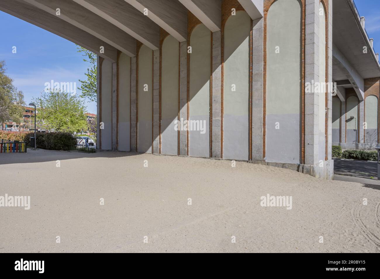 An urban corner with sand on the ground under the walls of a bridge ...
