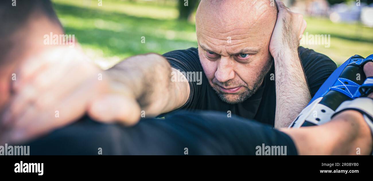 Muay thai trainer holds focus mitts. Elbow kick technique training and ...