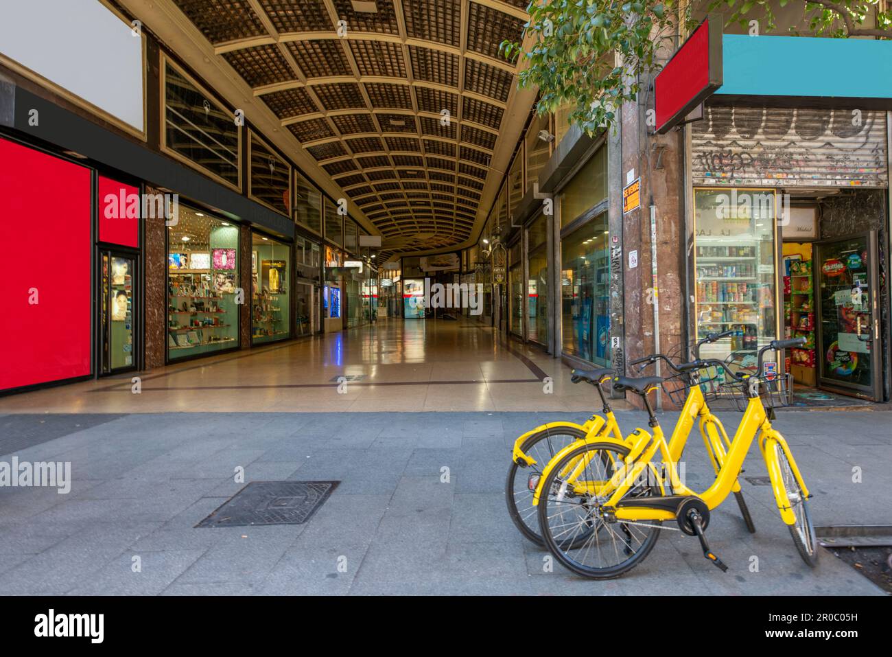 Street entrance to a shopping arcade and twin yellow bikes parked on ...