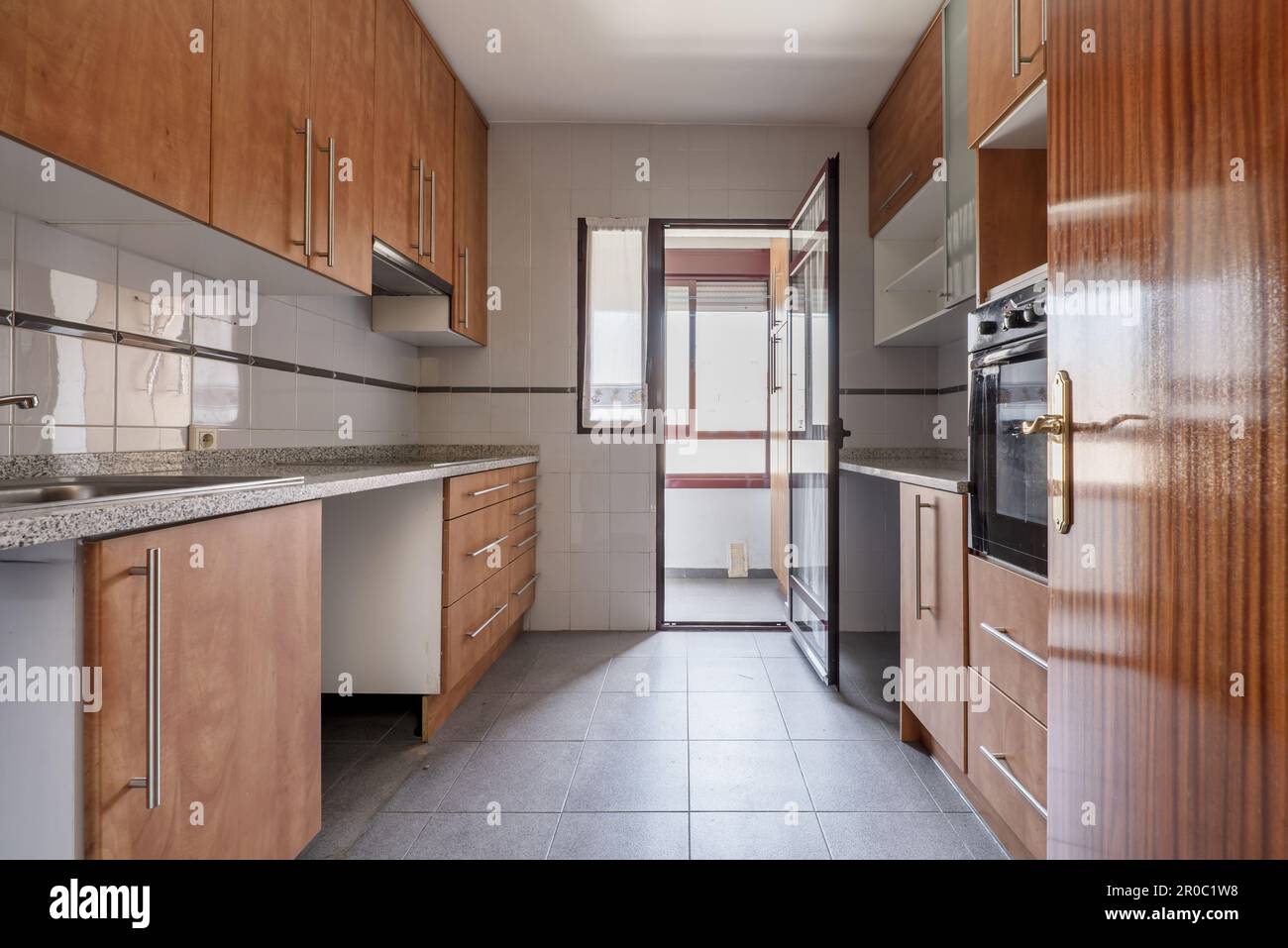 Kitchen furnished with wood-colored furniture and granite countertops ...