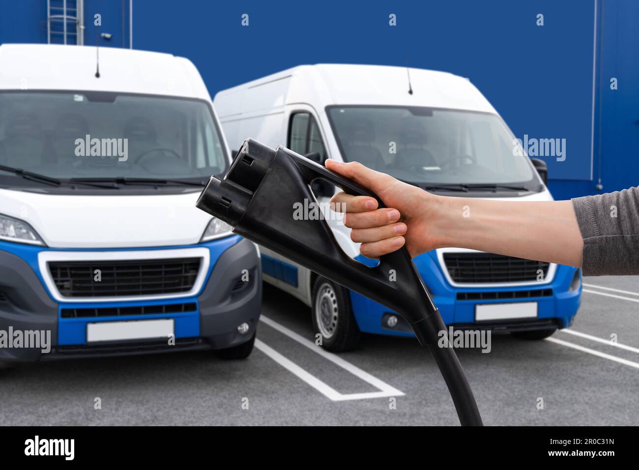 Hand with electric vehicles charging plug on a background of electric ...