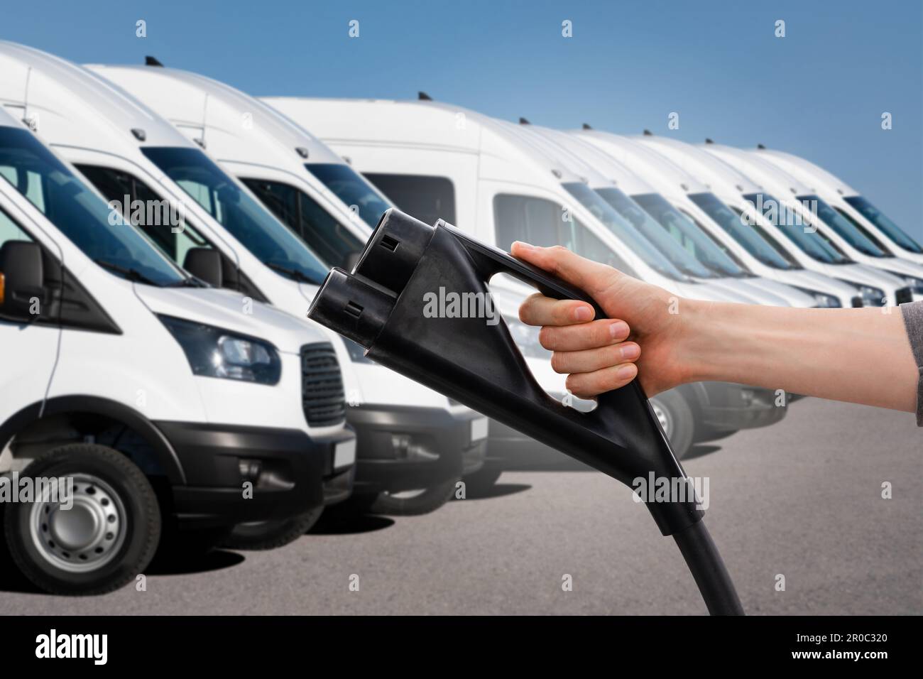 Hand with electric vehicles charging plug on a background of electric ...