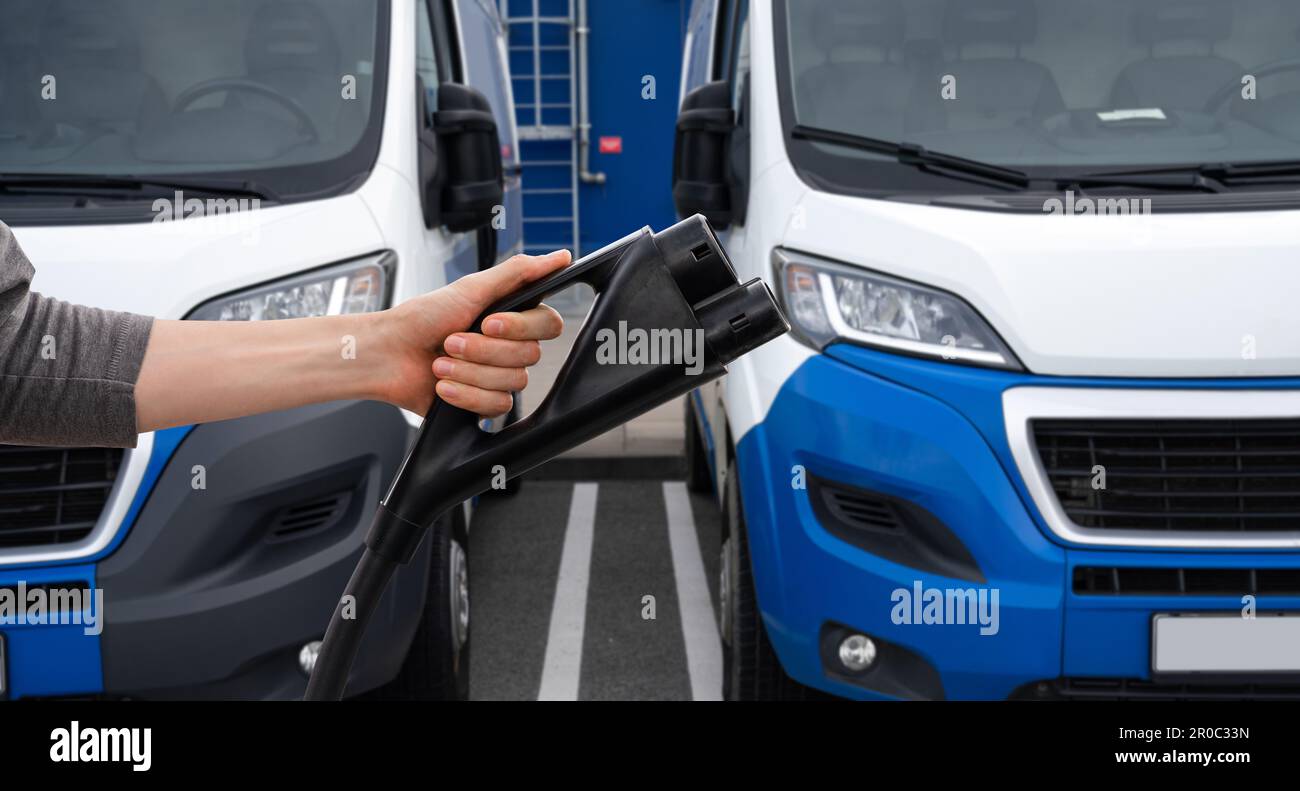 Hand with electric vehicles charging plug on a background of electric ...