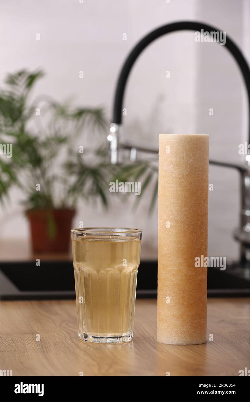 Used cartridge in rust and glass of dirty water on tabletop on kitchen ...