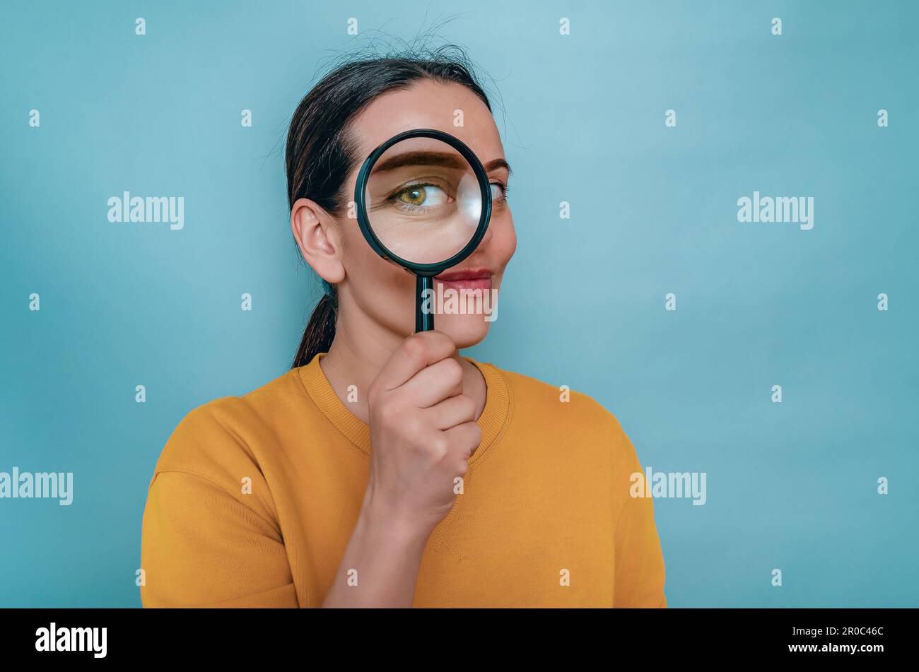 Magnifying glass. Woman's face through magnifying glass. Big eyes ...