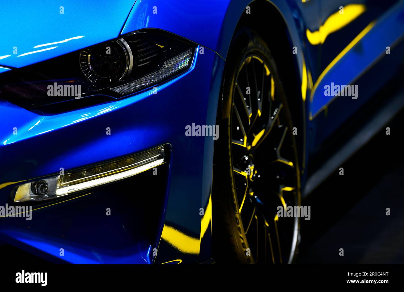 Front view of the LED headlights modern blue car on black background ...